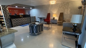 Um hall de hotel moderno com uma recepção, área de estar e um grande candelabro.