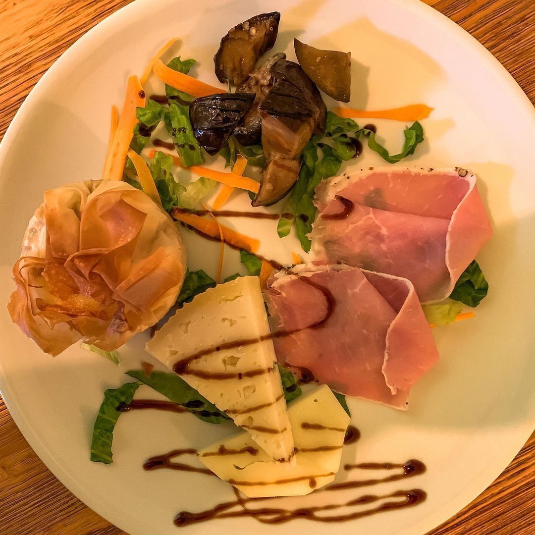 Um prato com diversos alimentos, incluindo vegetais, queijo e carne.
