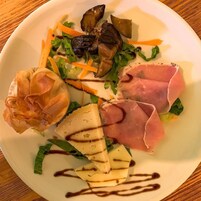 Um prato com diversos alimentos, incluindo vegetais, queijo e carne.
