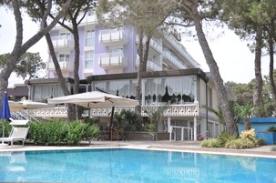 Um hotel com área de piscina, mobiliário de exterior e varanda com vista para a piscina.