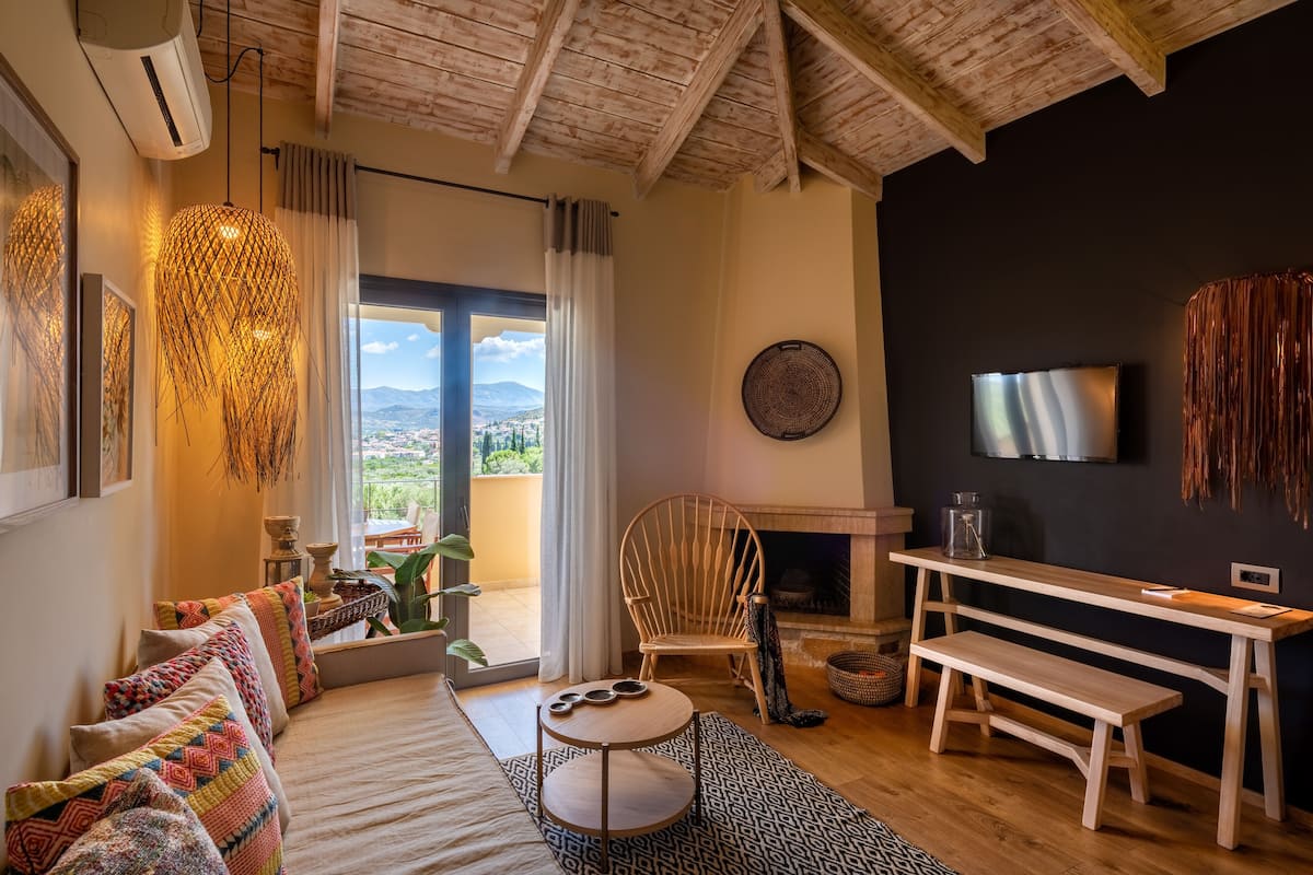 Uma sala de estar acolhedora com teto de madeira, lareira, televisão e vista para o exterior.