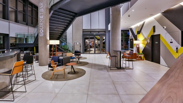 Interior moderno com escadaria central, áreas de estar e acesso visível a um bar.
