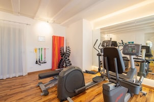 Uma academia com equipamentos de cardio, máquinas de peso e um espelho refletindo o espaço.