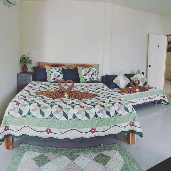 Cama bem arrumada com um edredom com padrão geométrico e almofadas em formato de coração.