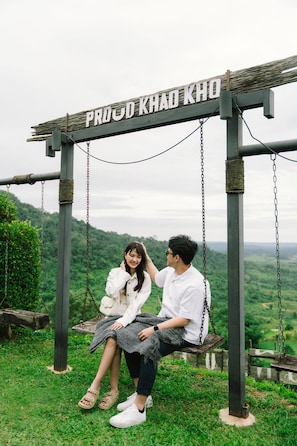Um casal sentado em um balanço com uma placa acima deles que diz "PROUD KHAD KHOO".