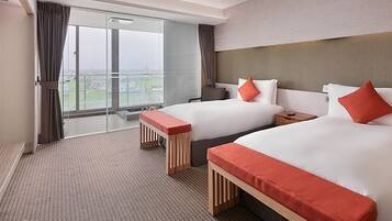 Quarto de hotel com duas camas, televisão e varanda com vista.