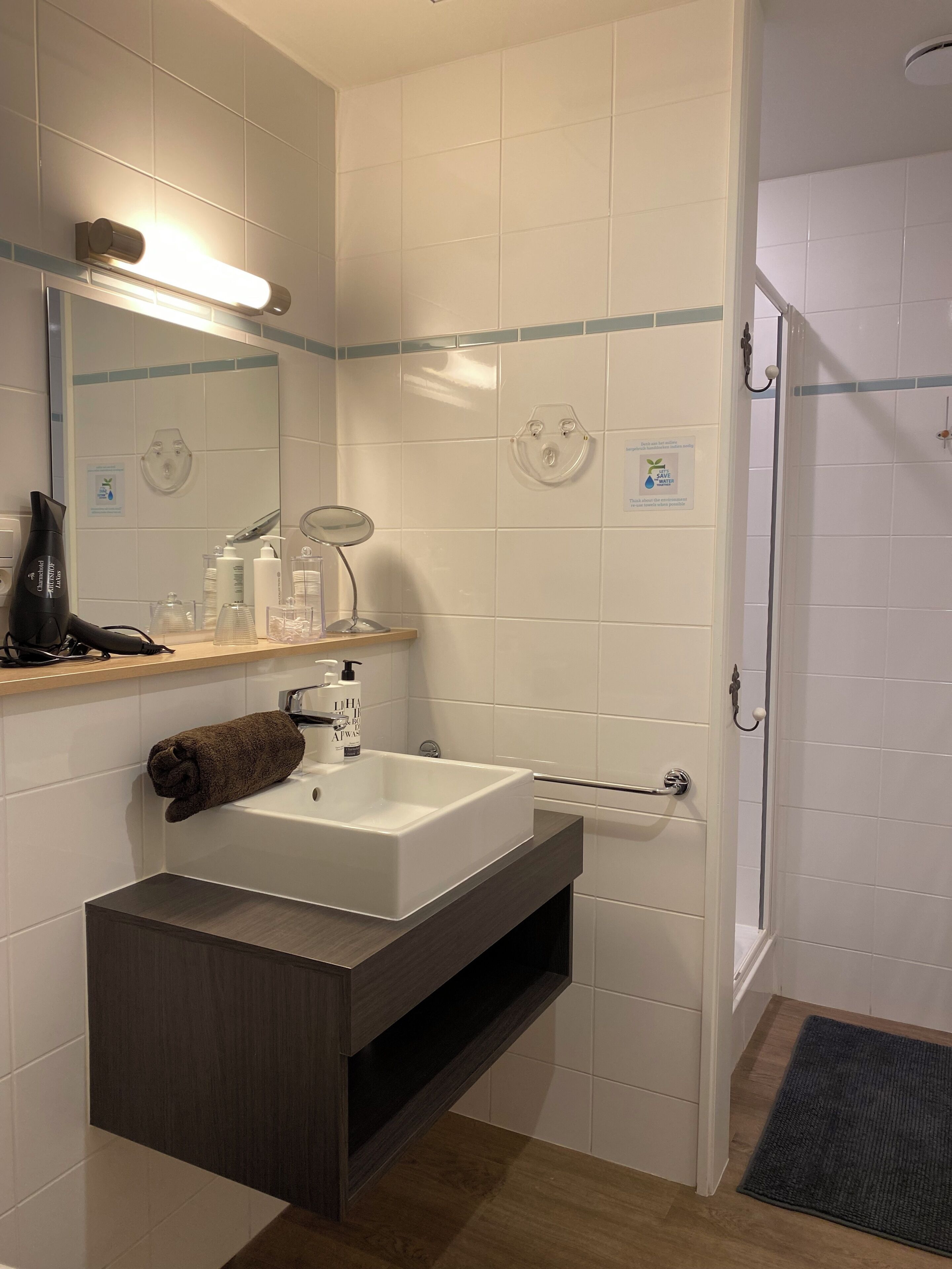 Casa de banho com lavatório branco, espelho e suporte para toalhas.
