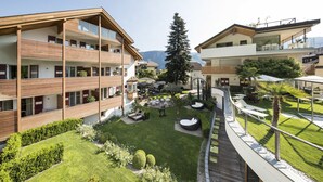 Um complexo de apartamentos moderno com várias varandas, áreas de estar ao ar livre e um jardim bem cuidado.