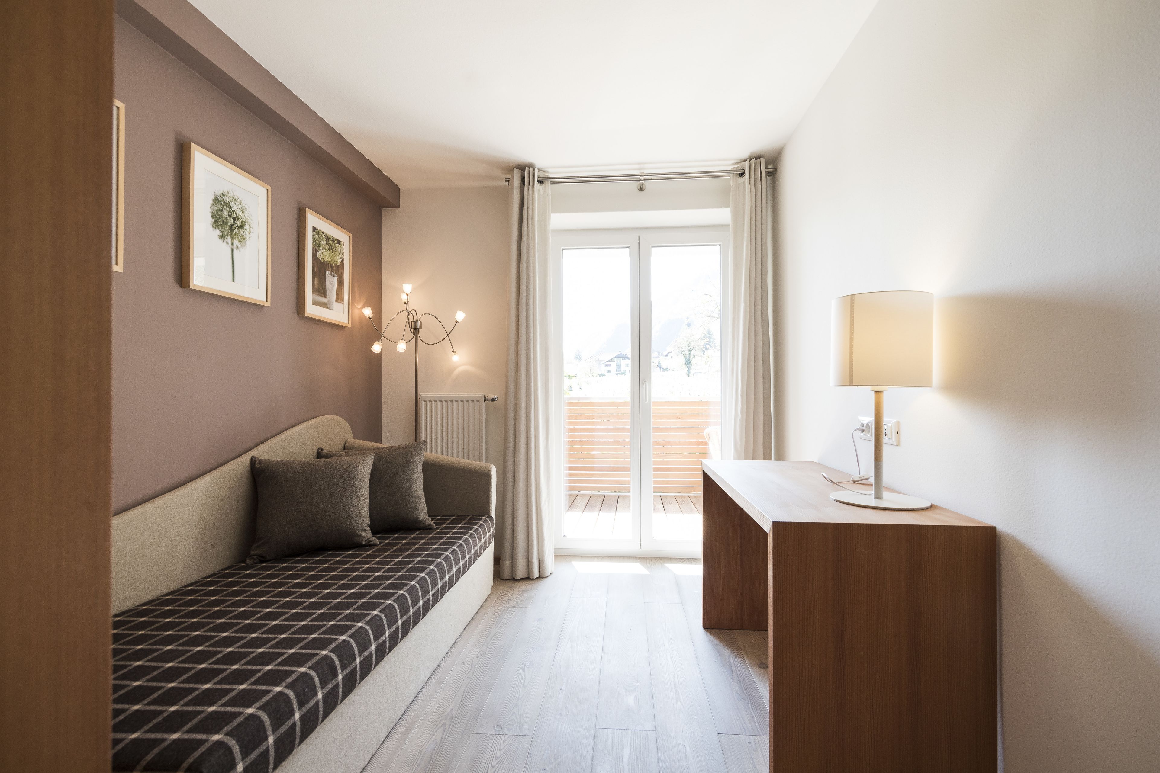Quarto moderno com sofá, escrivaninha e vista para o exterior.