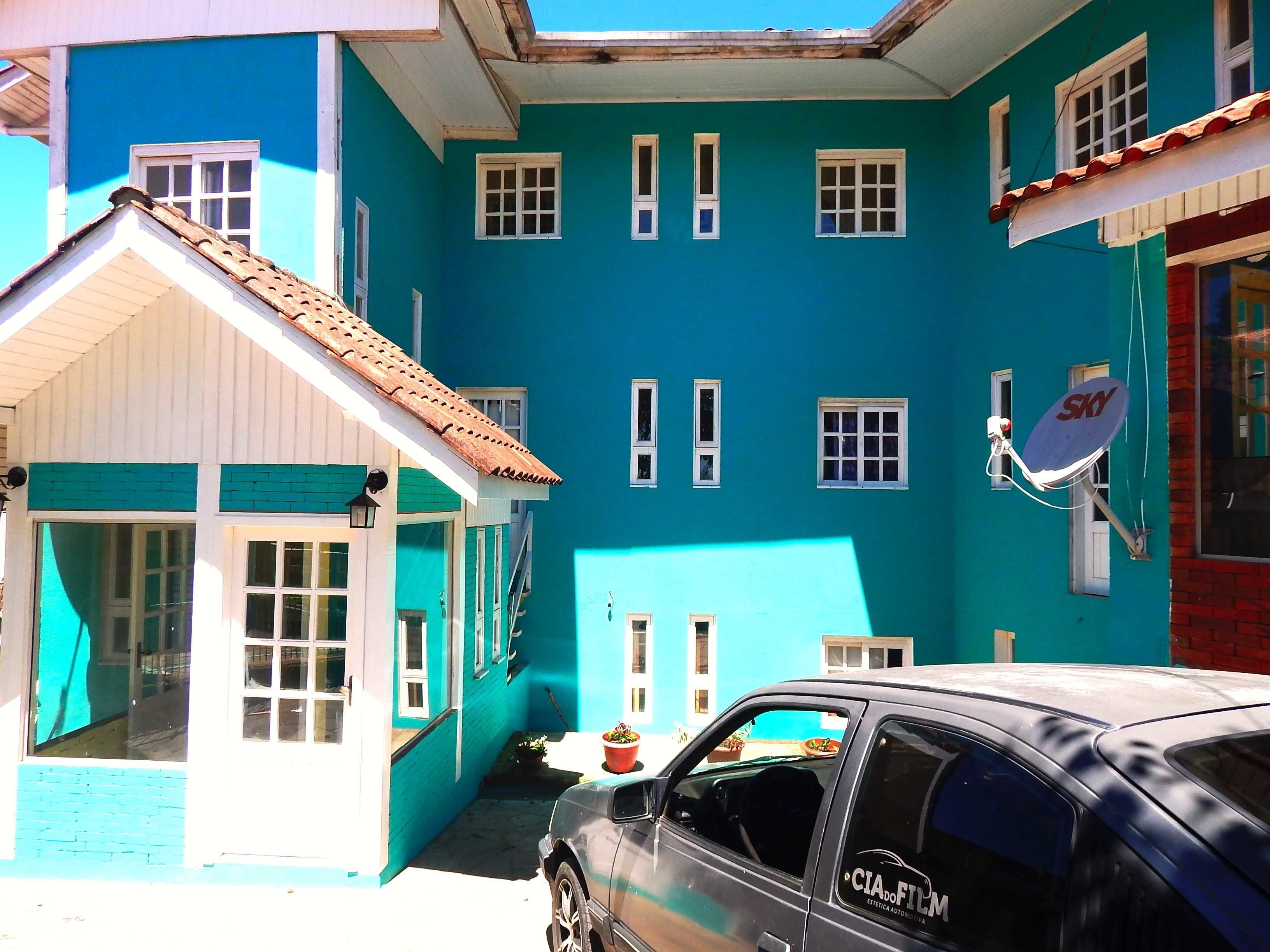 Rua estreita com um edifício azul com várias janelas e uma antena parabólica.