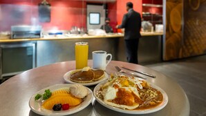 Mesa com pratos de comida, uma xícara de café e um copo de suco.