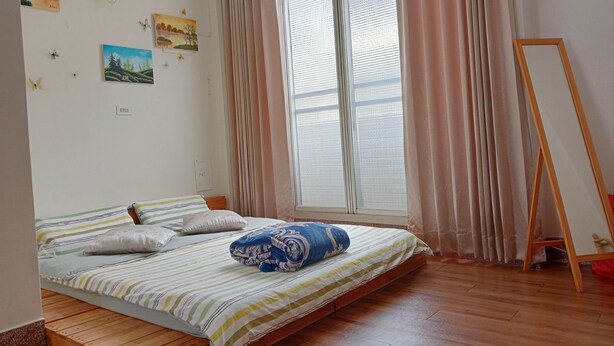 Quarto com cama, cortinas, janela e decorações nas paredes.