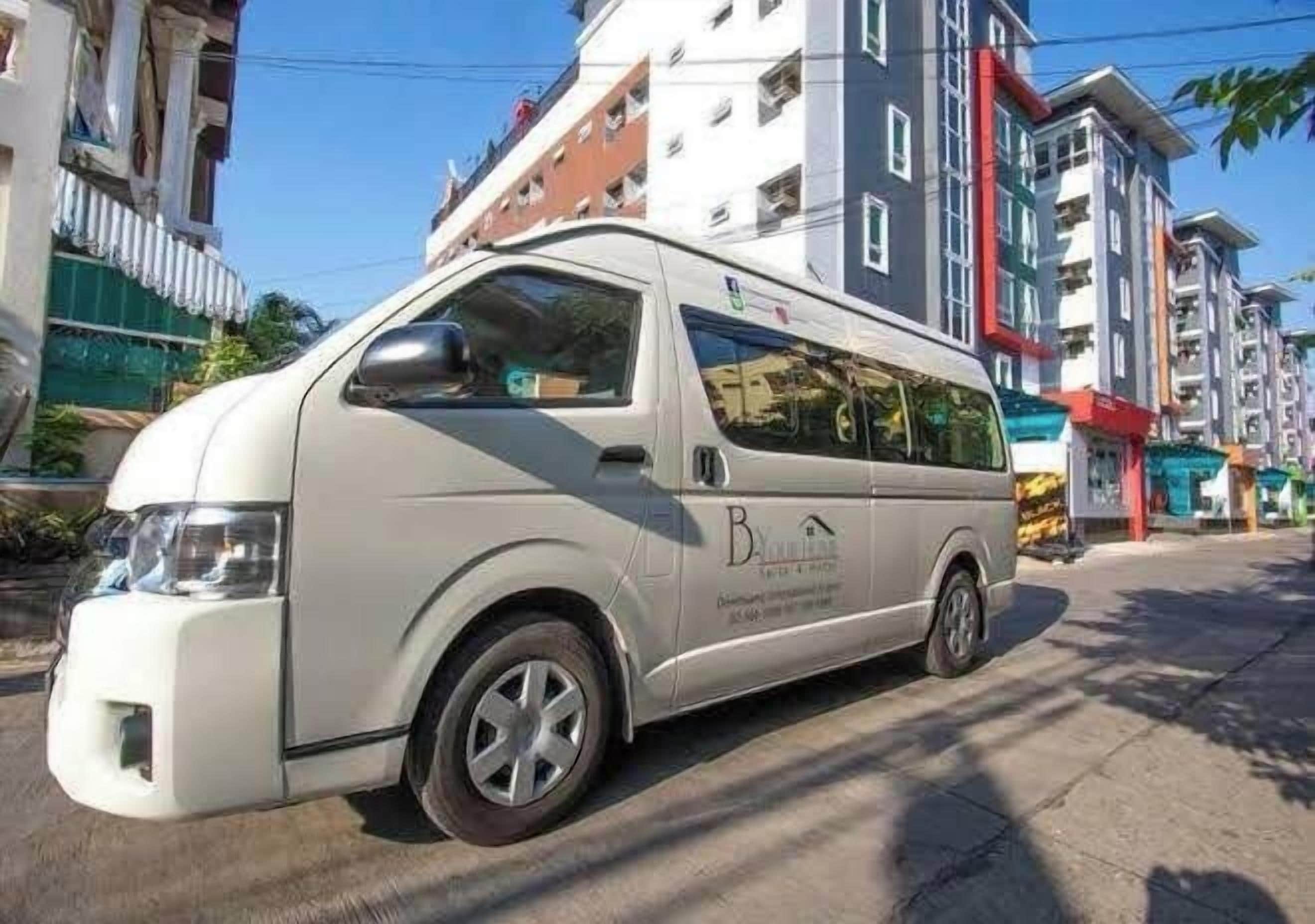 Uma carrinha branca estacionada numa rua com edifícios ao fundo.