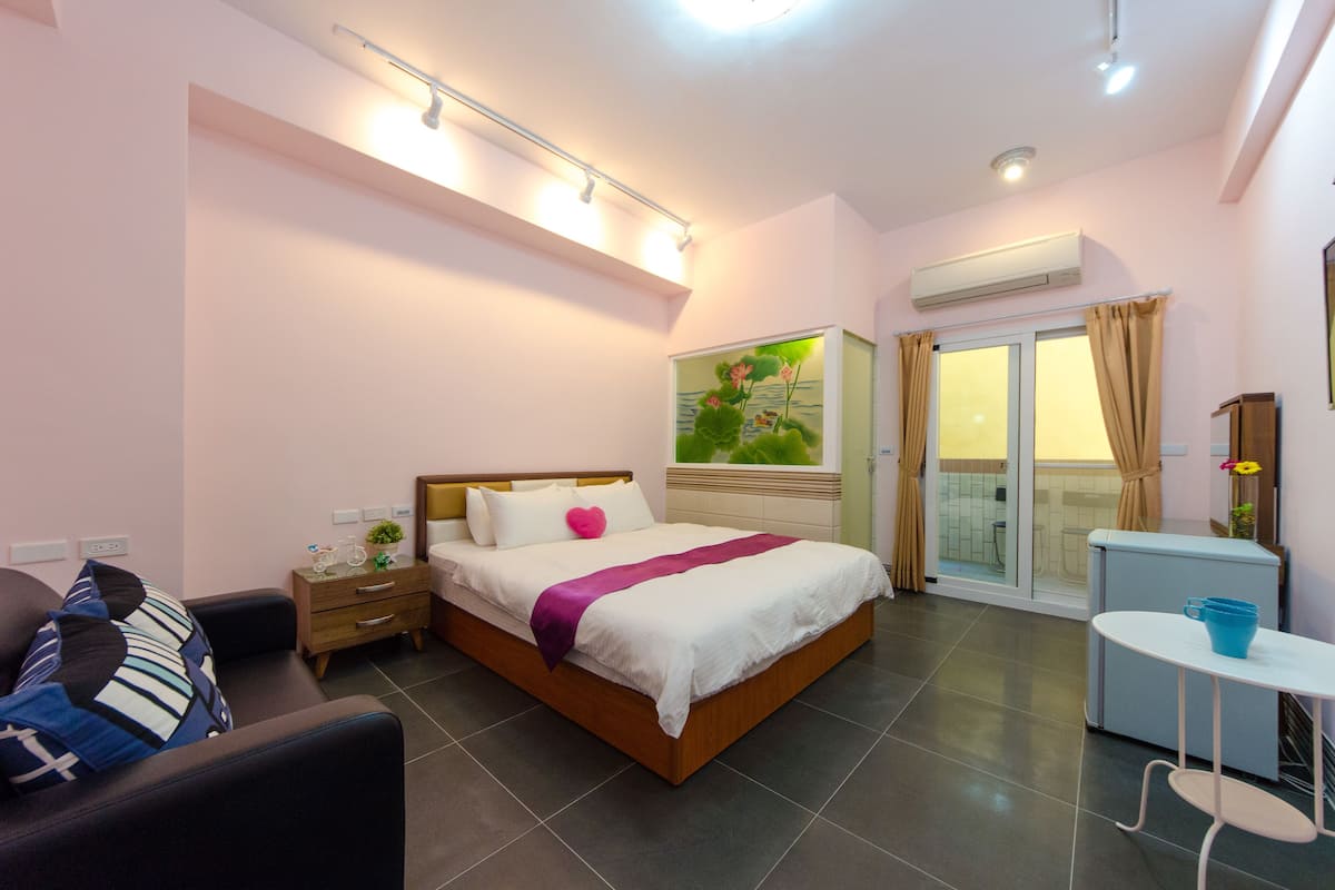 Um quarto moderno com uma cama, mesas de cabeceira, uma pequena escrivaninha e uma cadeira.