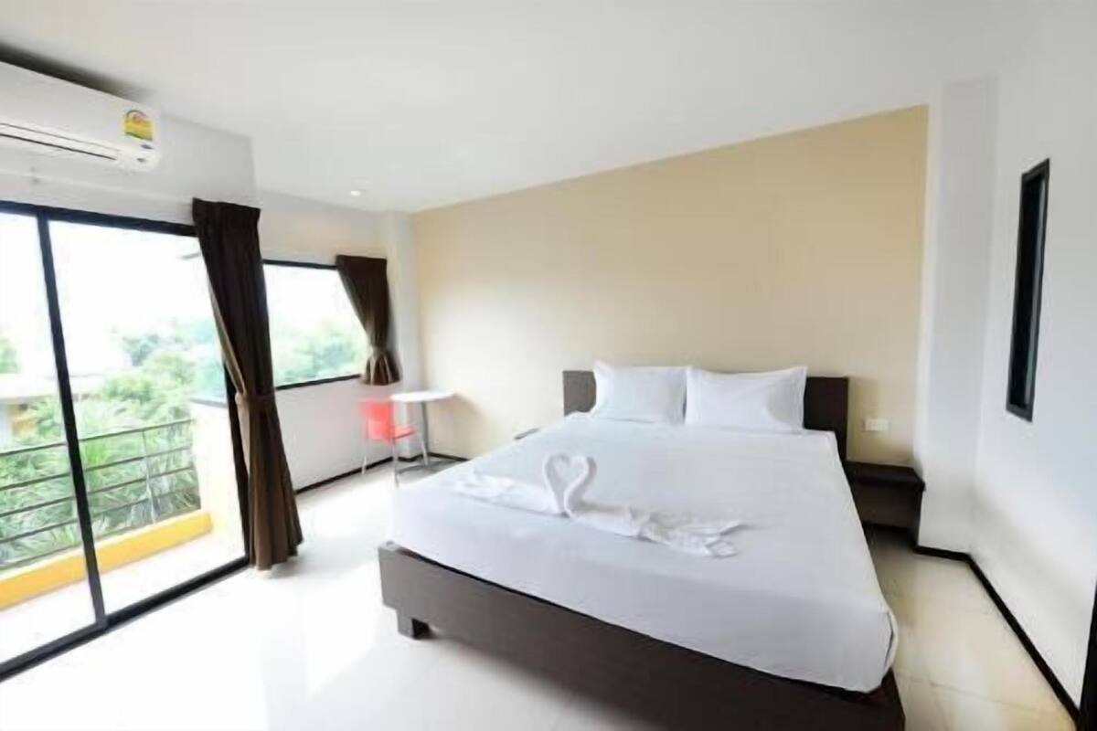 Quarto de hotel com cama grande, uma escrivaninha e varanda com vista.