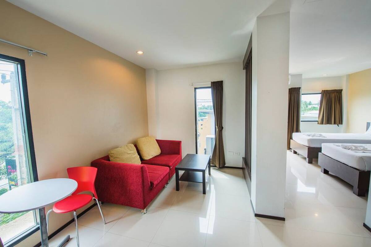 Quarto de hotel moderno com sofá vermelho, uma mesinha e uma cama.