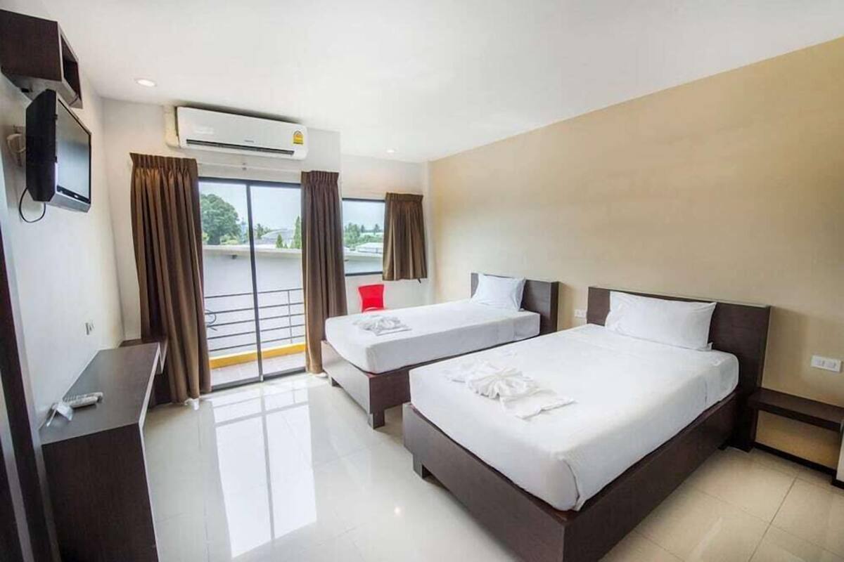 Quarto de hotel com duas camas, uma escrivaninha, ar condicionado e televisão.