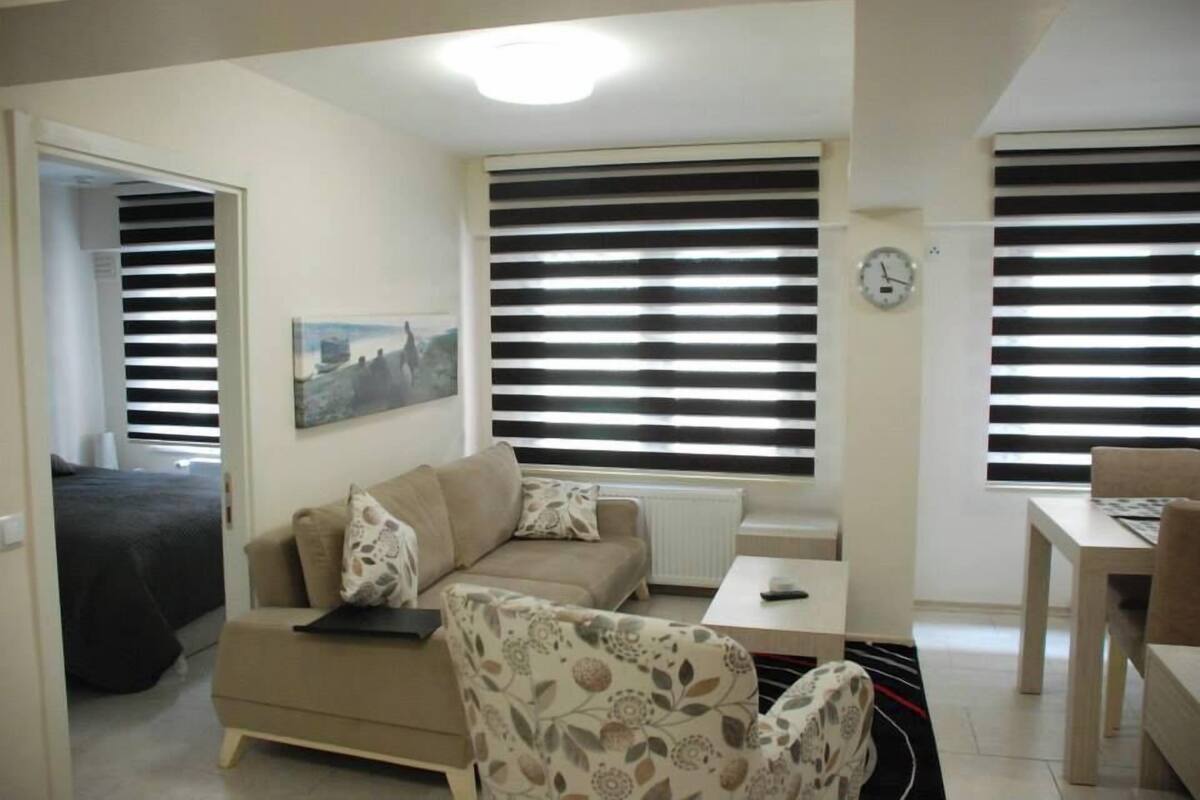 Uma sala de estar com sofá, mesa de centro e área de jantar com mesa e cadeiras.