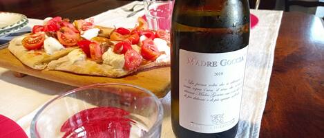 Uma garrafa de vinho, um copo e uma pizza sobre a mesa.