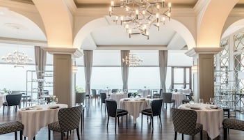Restaurante com mesas redondas, cadeiras estampadas e um candelabro.