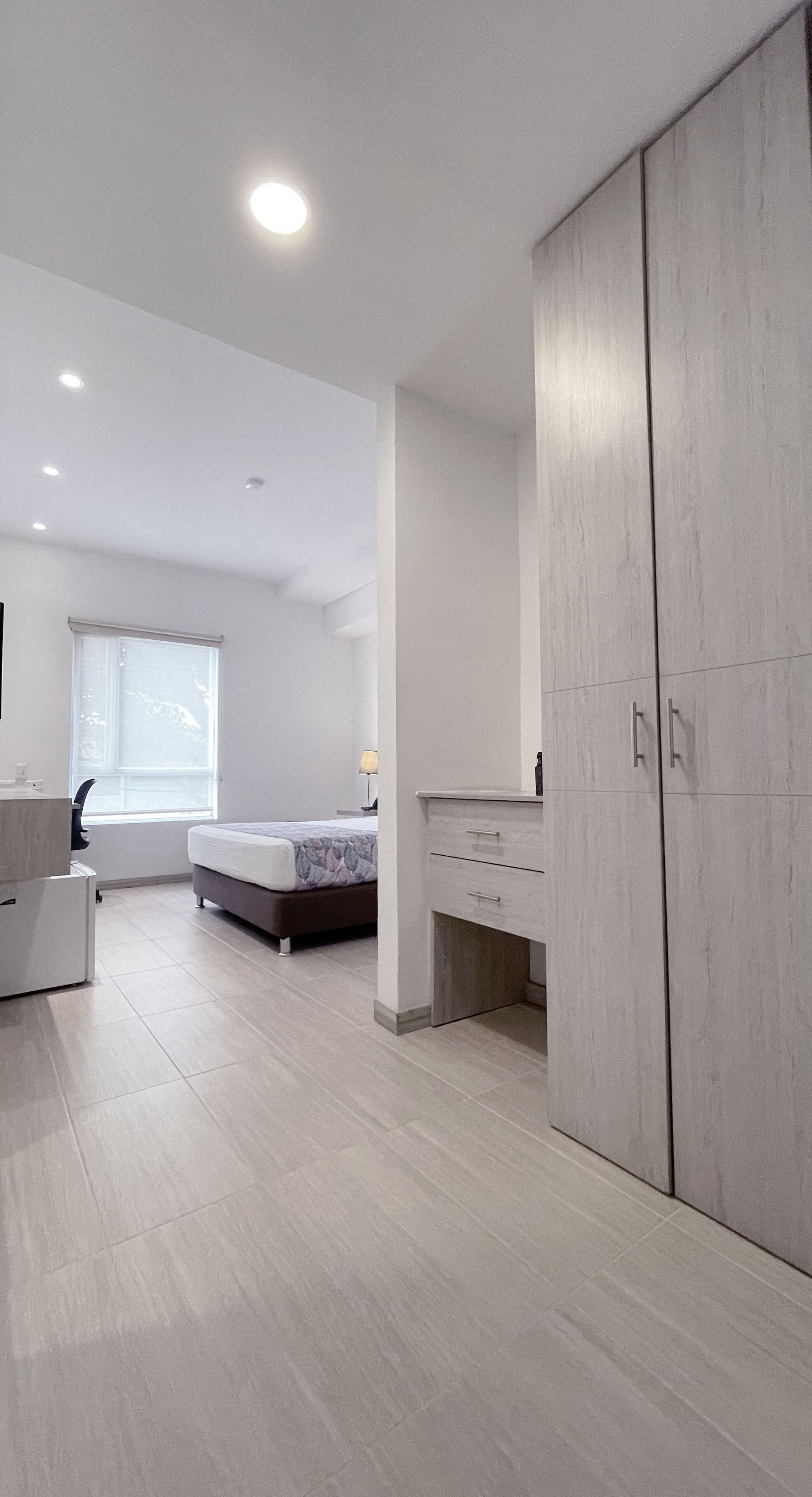 Quarto moderno com cama, guarda-roupa e área de trabalho.