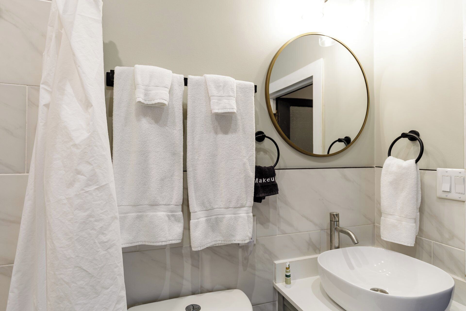 Casa de banho com lavatório branco, espelho e duas toalhas penduradas num suporte.