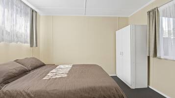 Quarto de hotel com cama, guarda-roupa e janela com cortinas.