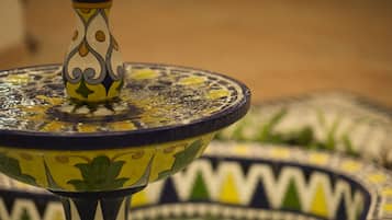 Close-up de uma fonte de cerâmica decorativa, com padrões elaborados e superfície refletora.