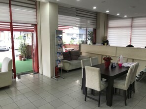 Um restaurante com área de refeições, incluindo uma mesa, cadeiras, um sofá e um extintor de incêndio.