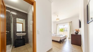Quarto de hotel com banheiro, uma cama, mesa de cabeceira e vista para o exterior.