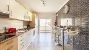 Cozinha moderna com ilha central, forno embutido e máquina de café.