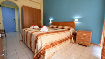 Quarto de hotel com cama, guarda-roupa de madeira, mesa de cabeceira e parede azul.