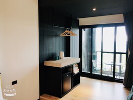 Quarto moderno com bancada de madeira, armários pretos e uma grande janela com vista para móveis de exterior.