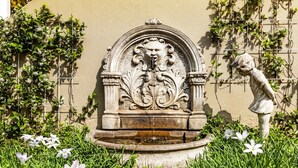 Uma fonte de pedra com arco decorativo e estátua de mulher.