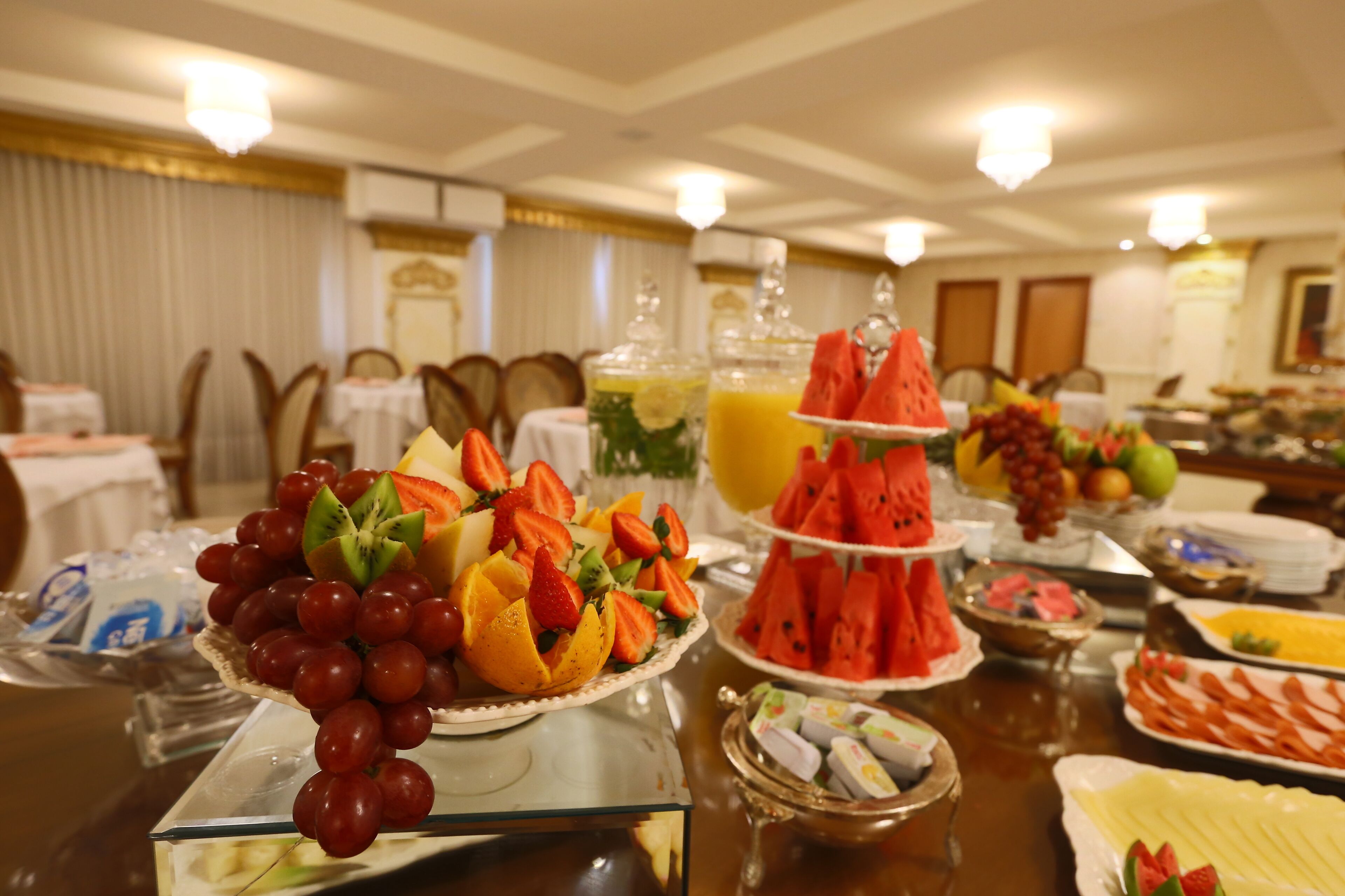 Mesa de buffet com diversas frutas e bebidas.