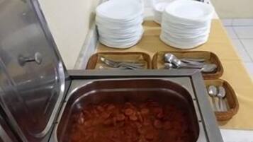 Uma mesa de buffet com diversos tipos de comida, incluindo um prato quente e pão fatiado.