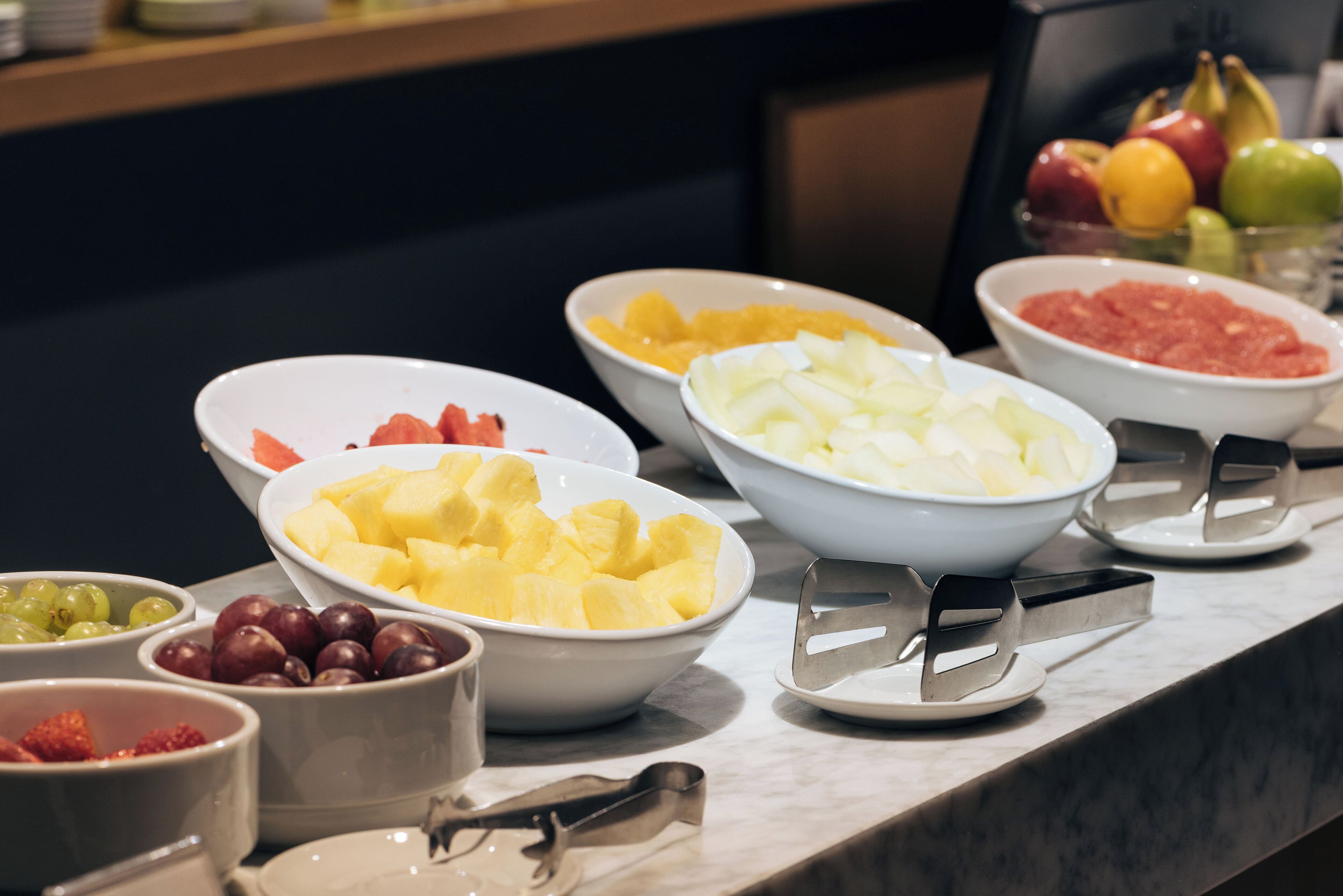 Buffet com diversas frutas e legumes em recipientes.