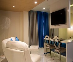Uma sala de estar moderna com um sofá branco, uma mesa de jantar com cadeiras, uma televisão de tela plana na parede e uma janela grande com cortinas azuis.