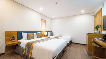 Quarto de hotel com duas camas, uma escrivaninha, um espelho e uma janela com persianas.