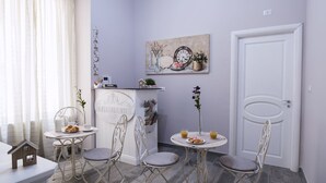 Uma área de refeições com uma mesa, cadeiras, um pequeno modelo de casa, um quadro e uma porta.