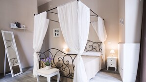 Quarto com cama de dossel, mesa de cabeceira, espelho e prateleira na parede.