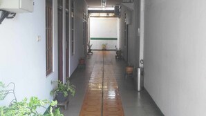 Um corredor com chão de azulejos, plantas em vasos e portas em ambos os lados.