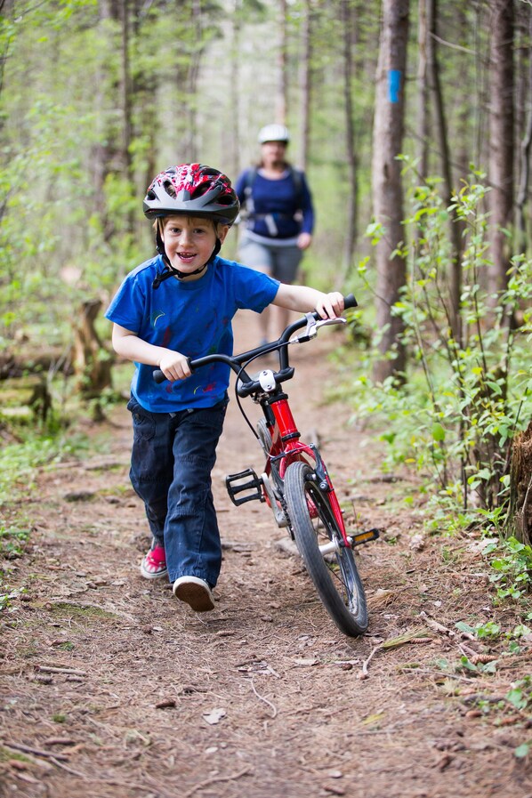 Uma criança andando de bicicleta numa trilha na floresta.