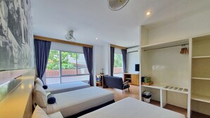 Quarto de hotel com duas camas, uma mesa, uma cadeira, uma televisão e um guarda-roupa.