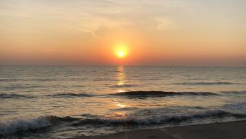 Um pôr do sol sobre o oceano, com ondas calmas e céu limpo.