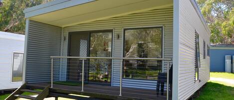 Uma casa móvel térrea com varanda coberta, quintal cercado e escada que dá acesso à entrada.
