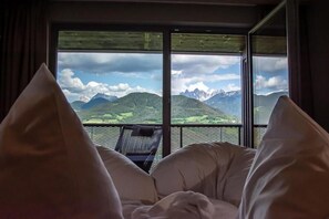 Cama com vista para montanhas através de uma janela.