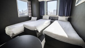 Quarto de hotel com duas camas de solteiro, uma mesa redonda pequena e uma janela grande com cortinas.