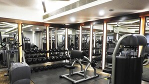 Uma academia com diversos equipamentos de ginástica, incluindo esteiras, halteres e aparelhos de musculação.