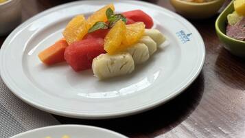 Uma mesa com diversos pratos, incluindo uma travessa de frutas e uma tigela de sopa.